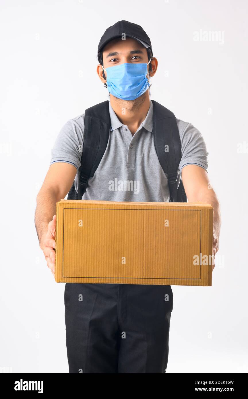 Courier boy delivering a parcel wearing a facemask Stock Photo - Alamy