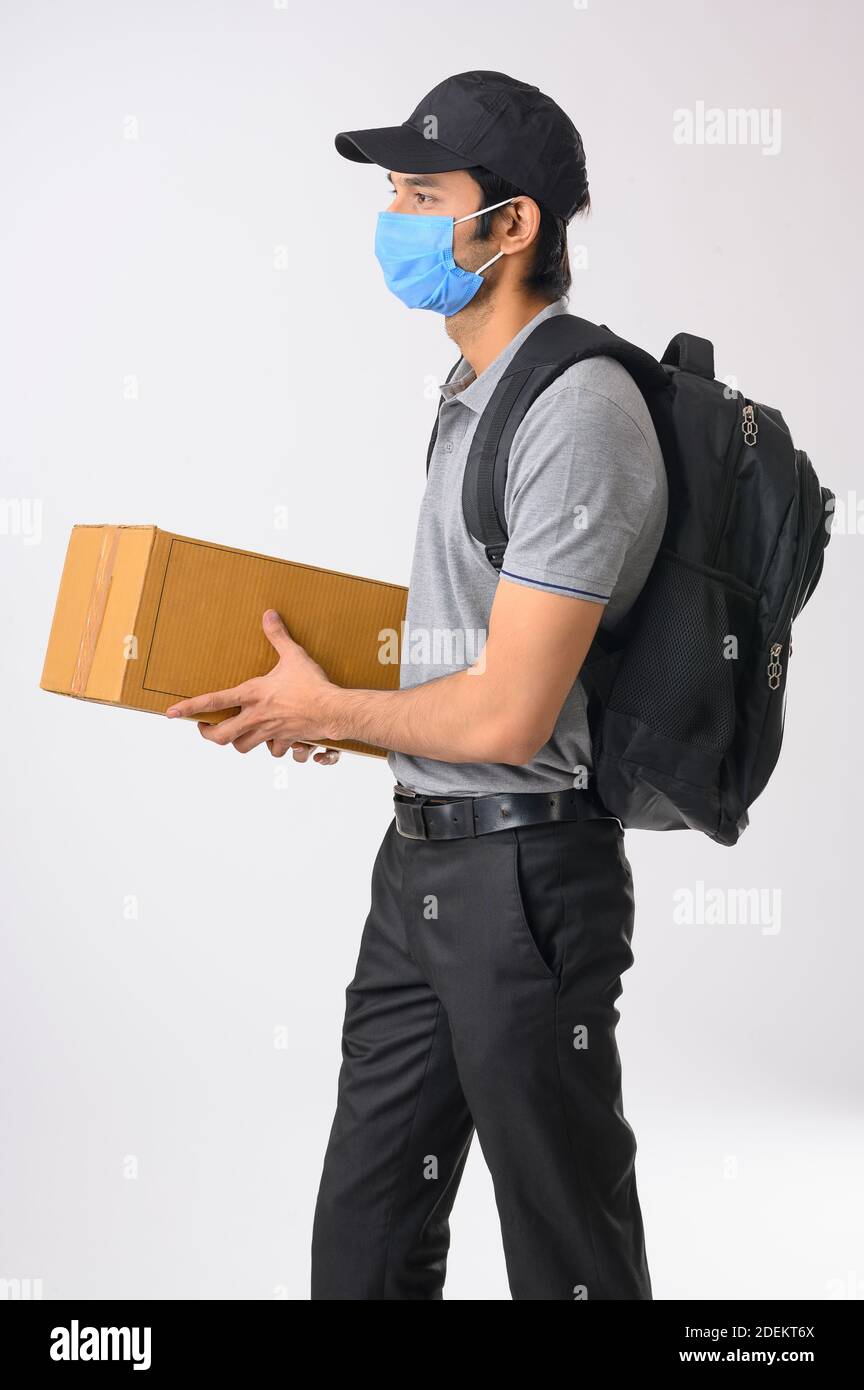 Courier boy walking with a package in his hand to be delivered wearing ...