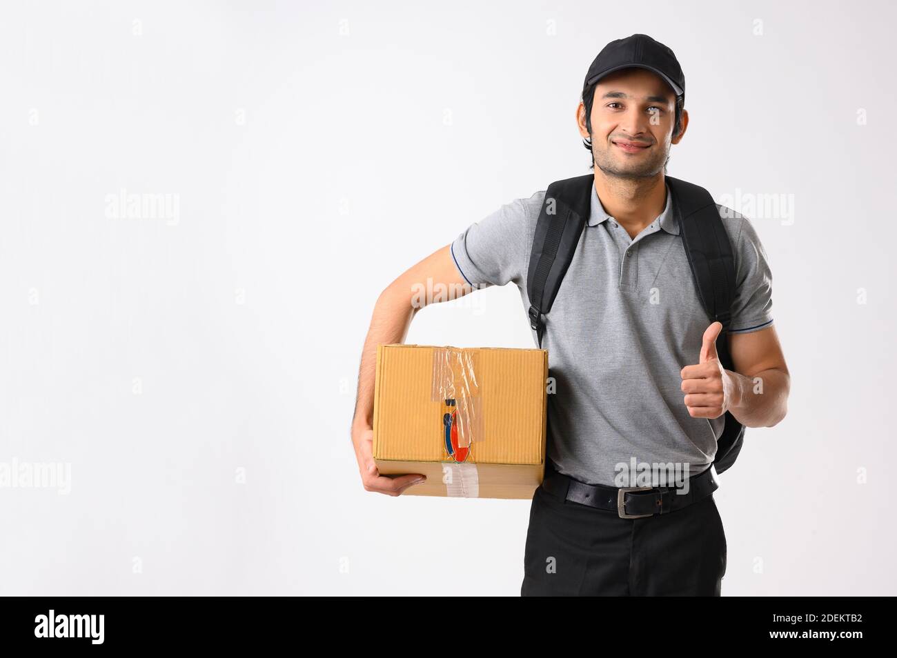 Delivery boy giving thumbs up with a box in one hand Stock Photo - Alamy