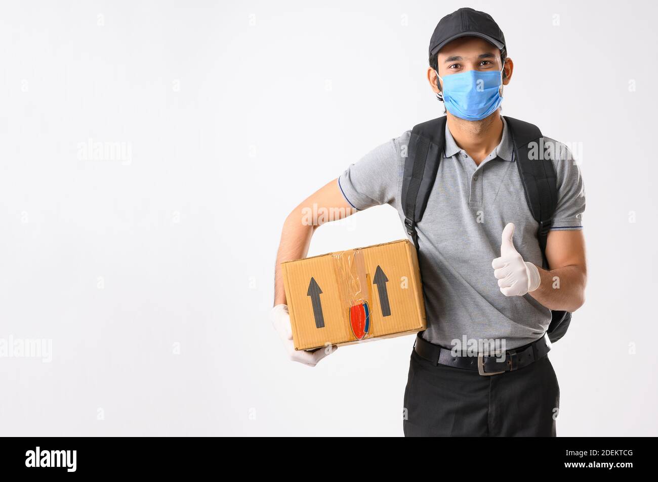 Delivery boy giving thumbs up with a box in one hand Stock Photo - Alamy