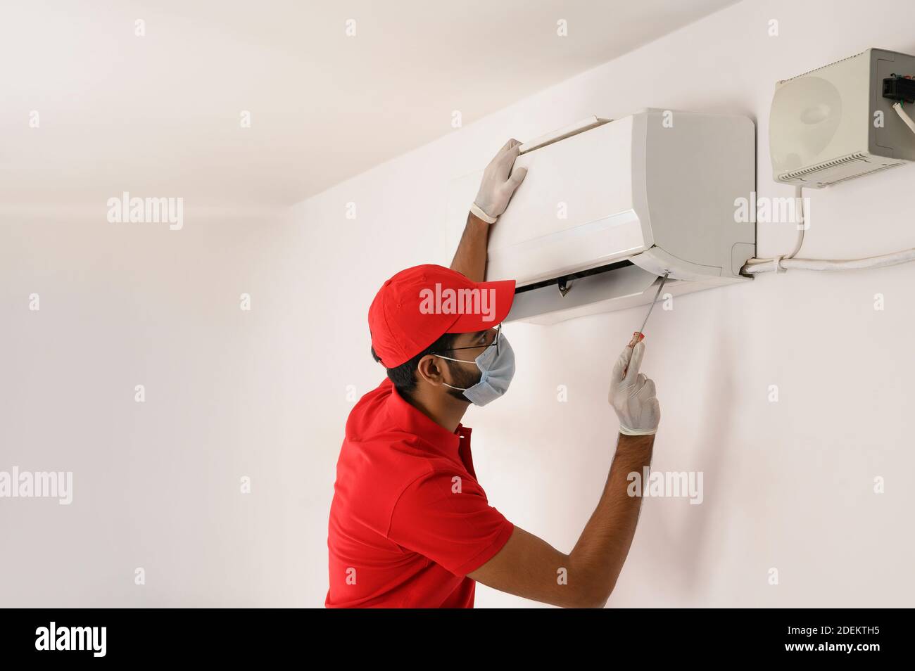Technician opening the air conditioner with a screwdriver to examine it ...