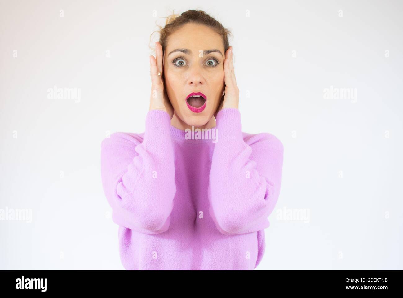 Portrait of a pretty young woman very surprised and scared on a white ...