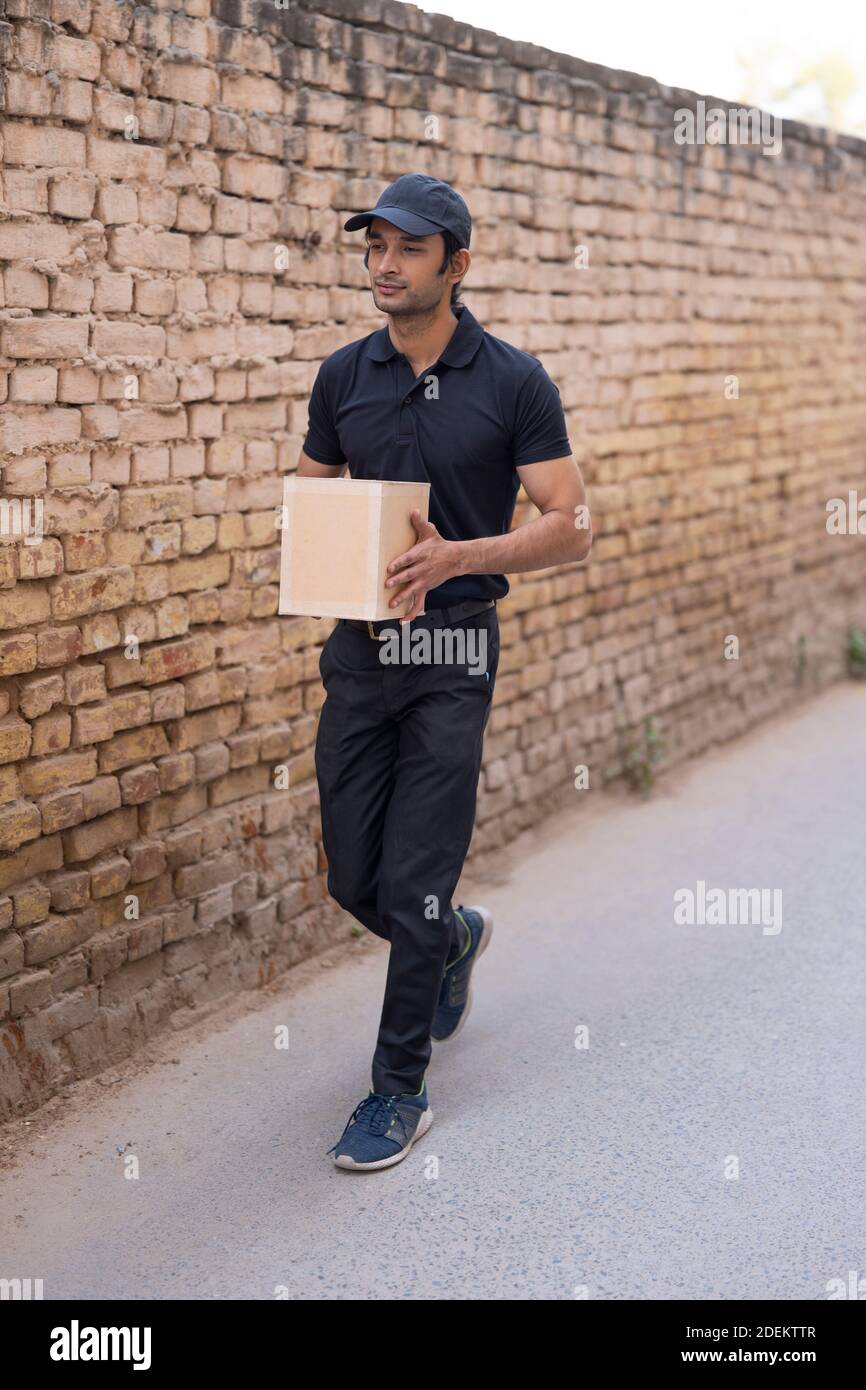 Courier boy walking with a parcel in his hand Stock Photo - Alamy