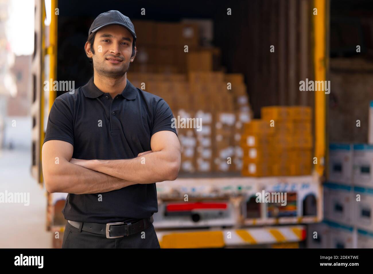 Courier boy standing with a parcel in his hand and smiling Stock Photo ...