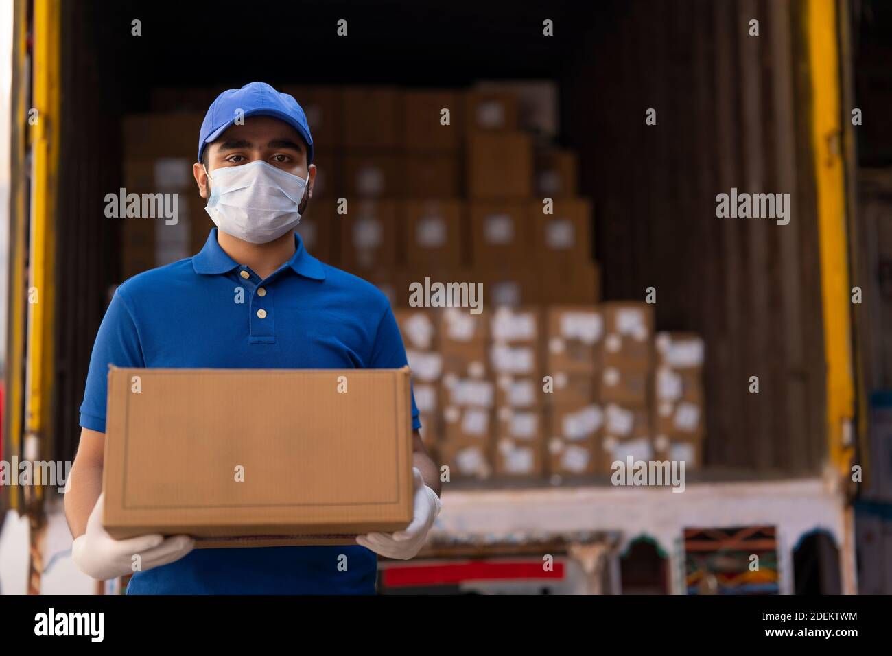 Courier boy standing with a parcel in his hand and smiling Stock Photo ...