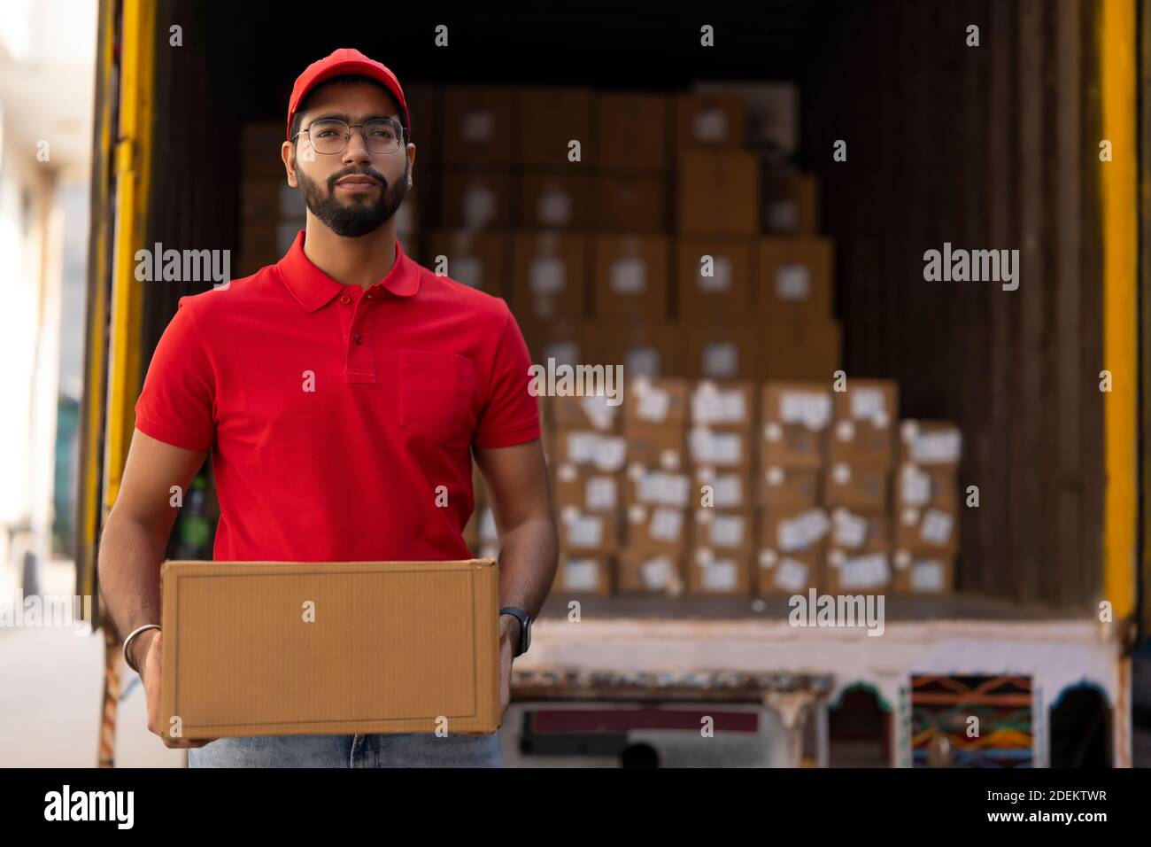 Courier boy standing with a parcel in his hand Stock Photo - Alamy