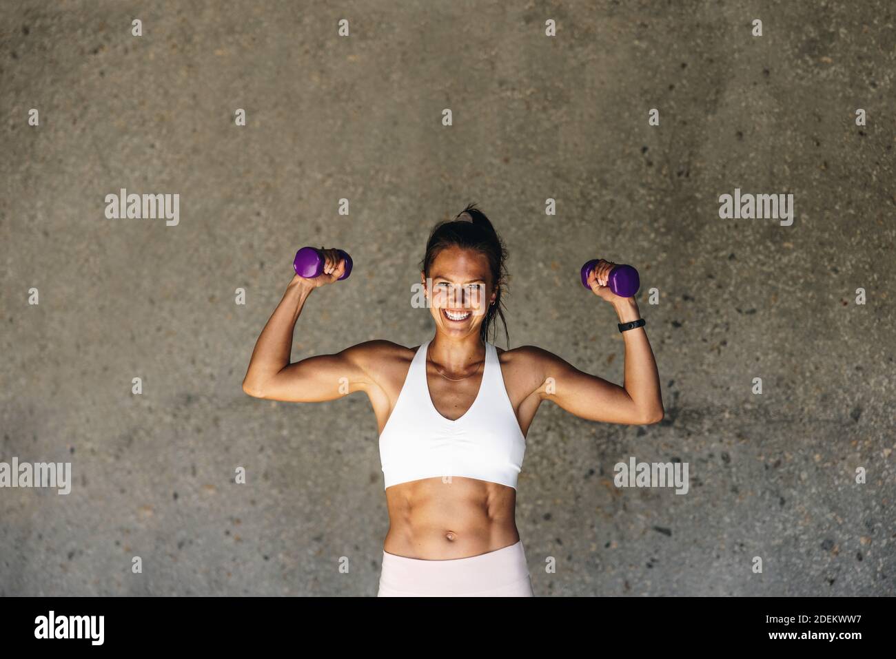 Smiling woman exercising with hand weights. Woman holding dumbbell ...