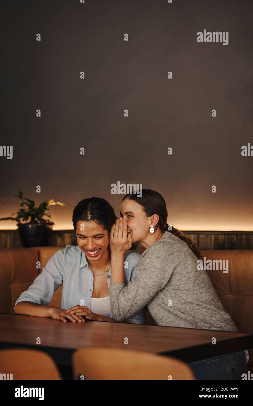 Two laughing young women whispering hi-res stock photography and images ...