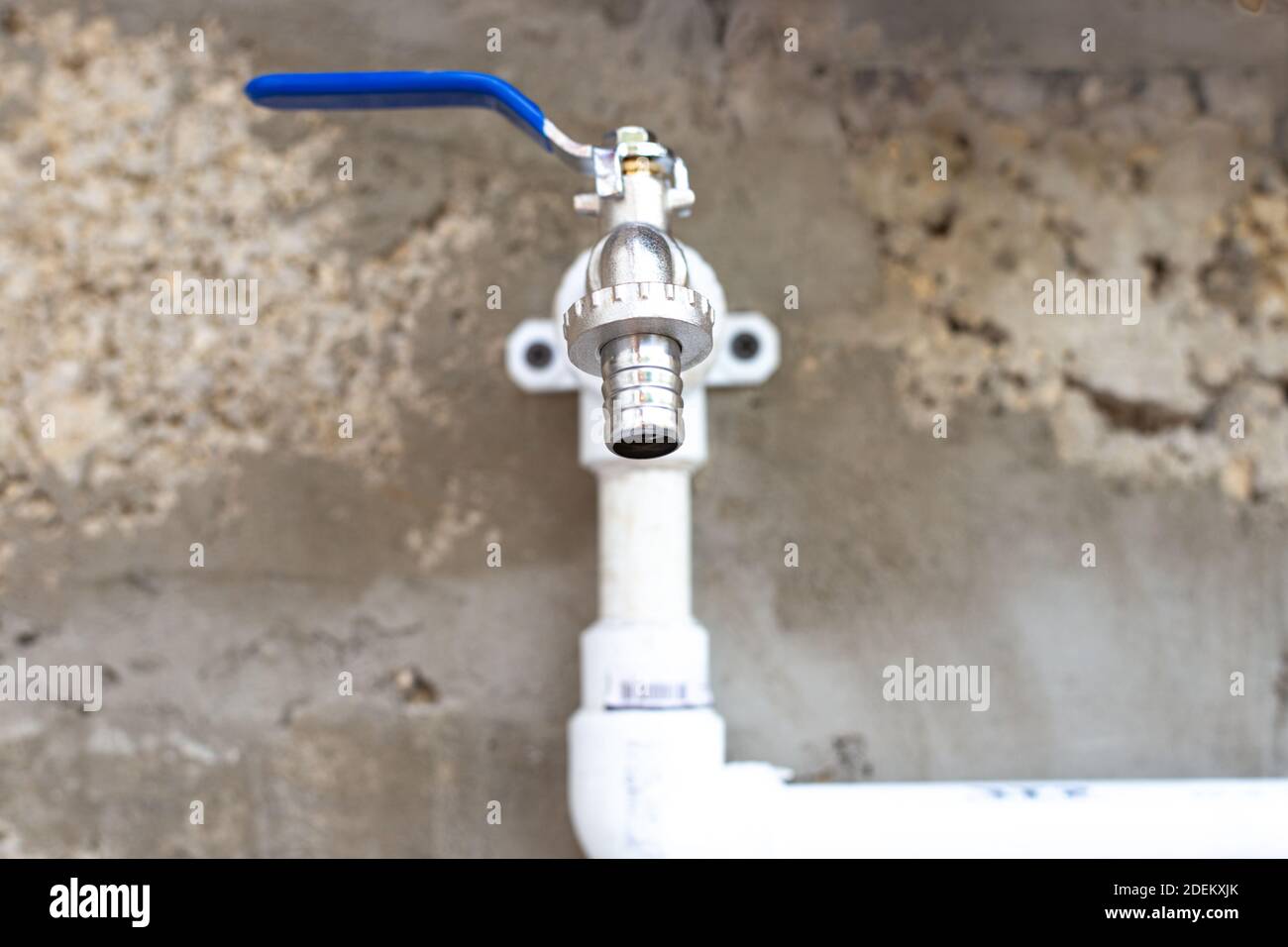 iron water tap, white PVC pipe against the background of a stone wall ...