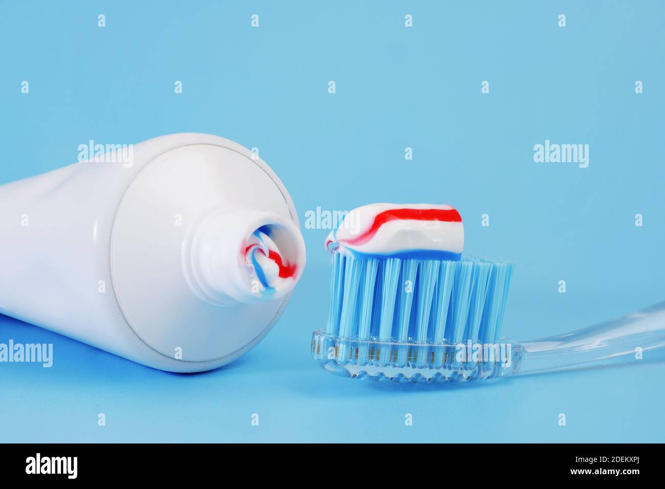 toothbrush with tricolor toothpaste on it and white toothpaste tube on ...