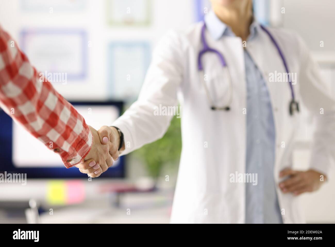 Doctor with stethoscope around neck shaking patients hand in clinic ...