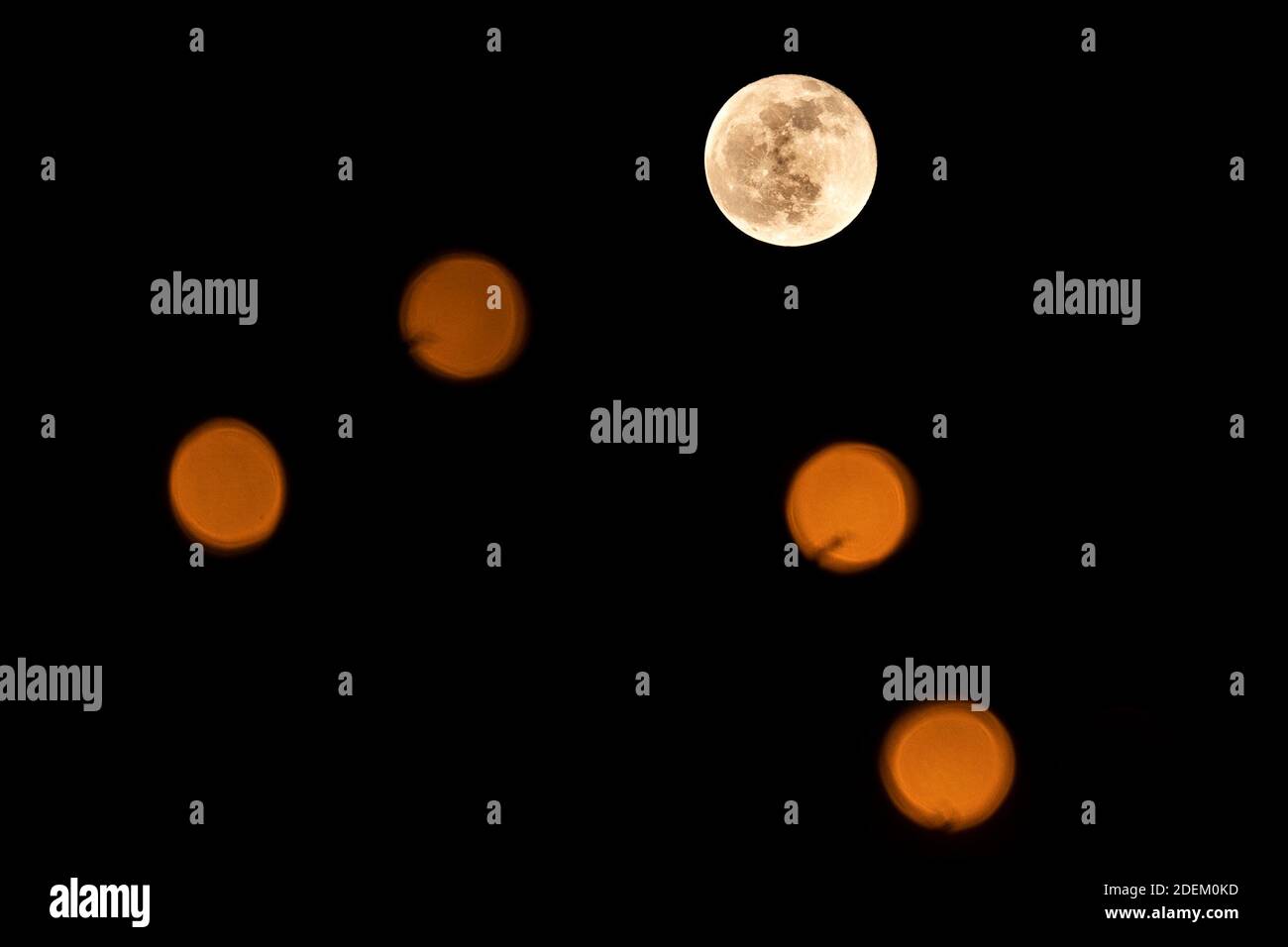 A full moon rises behind a decoration holiday light in Whittier ...