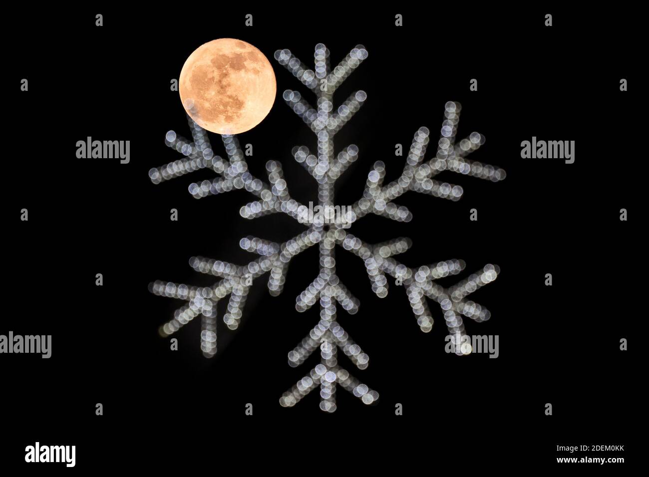 A full moon rises behind a decoration holiday light in Whittier ...