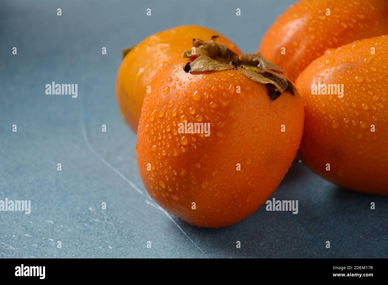 Three ripe persimmons on a blue background. Delicious fresh persimmon ...