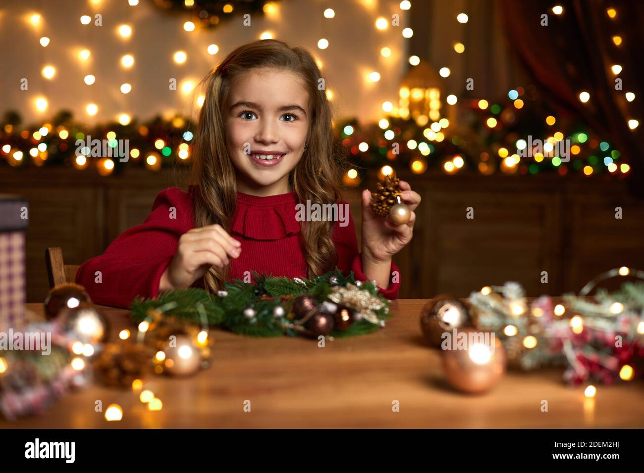 happy cute little child girl makes a handmade Christmas wreath at home ...