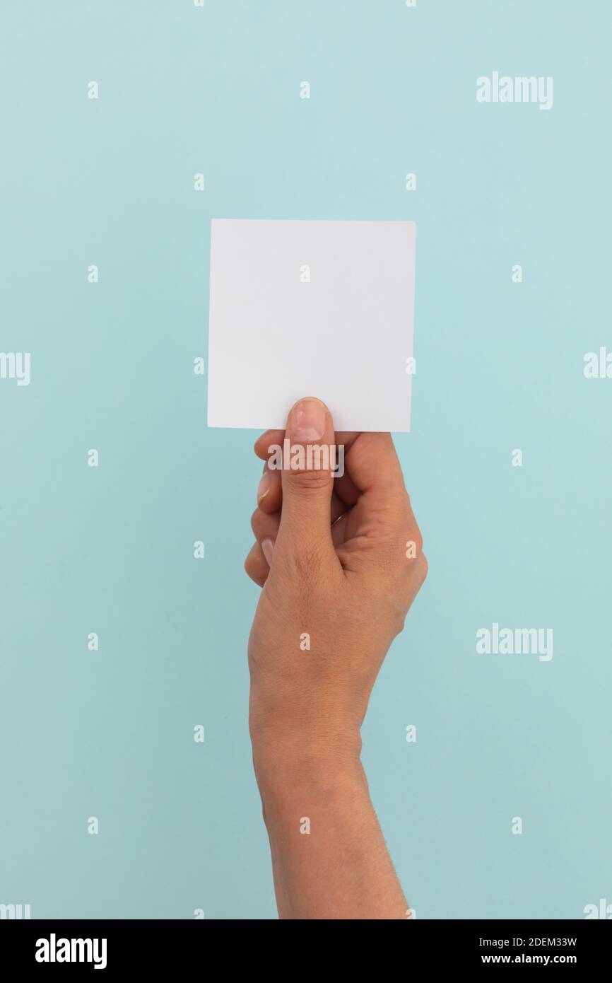 Hand of caucasian woman holding white paper over pale blue background ...