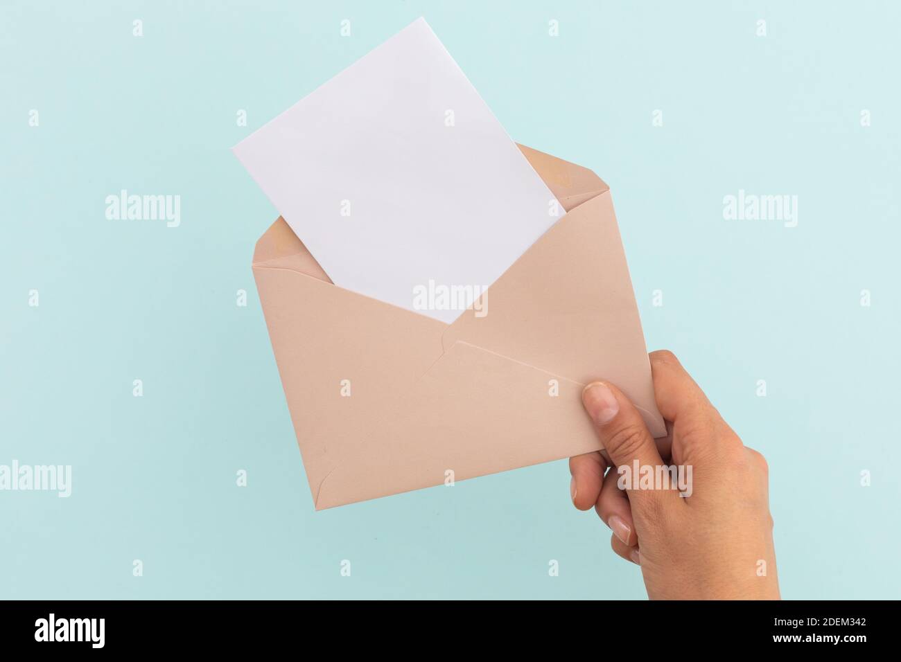 Hand of caucasian woman holding opened envelope with letter over pale ...