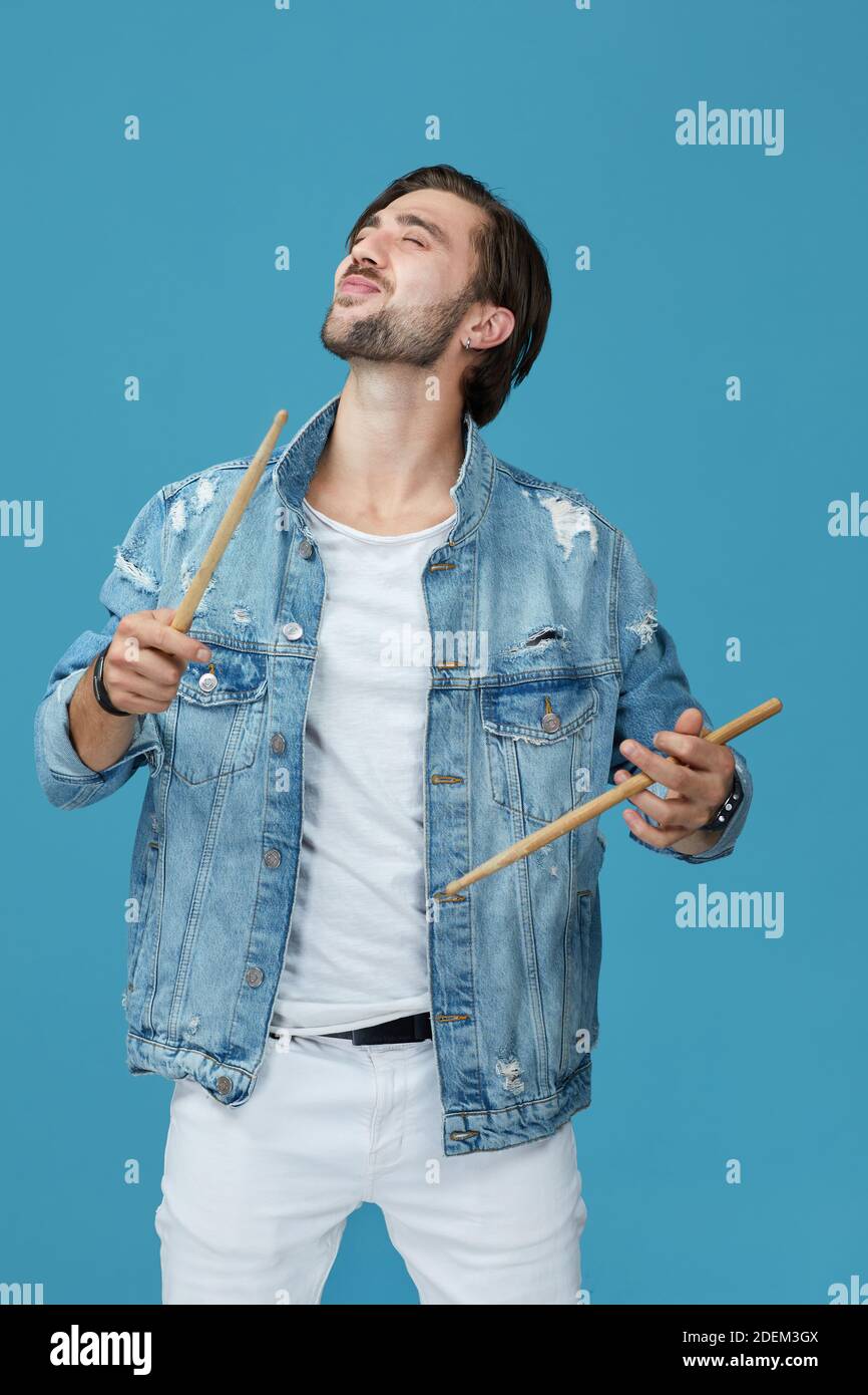 handsome male drummer improvising isolated on blue studio background ...