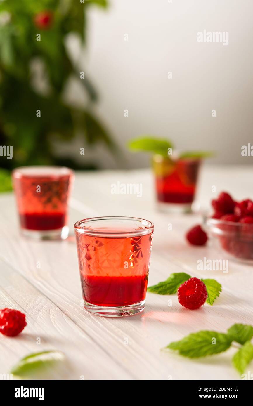 Raspberry alcoholic shots, shot glasses with colored liquor on a white ...