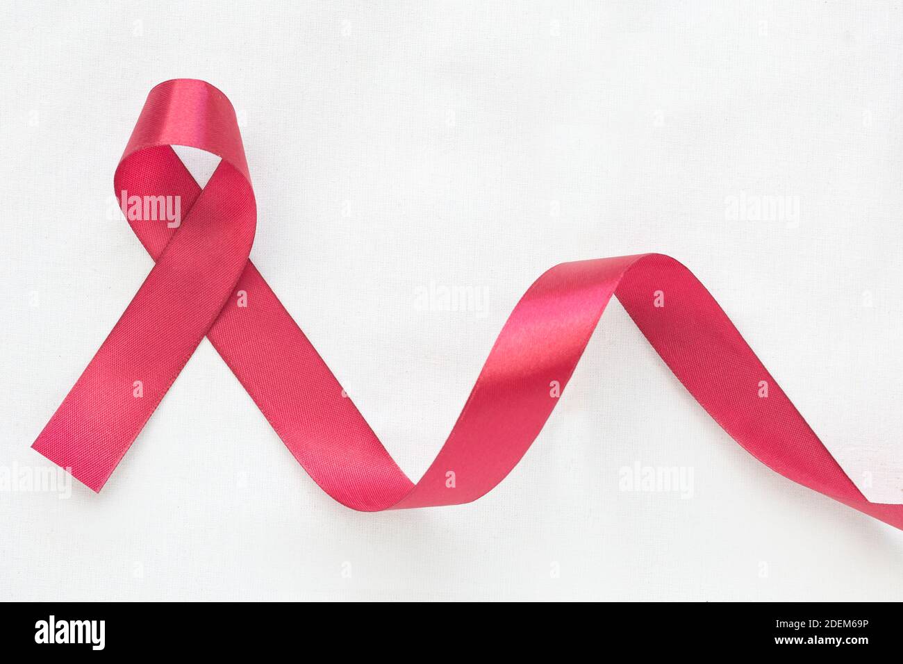 Red burgundy ribbon on white fabric background with copy space, symbol ...