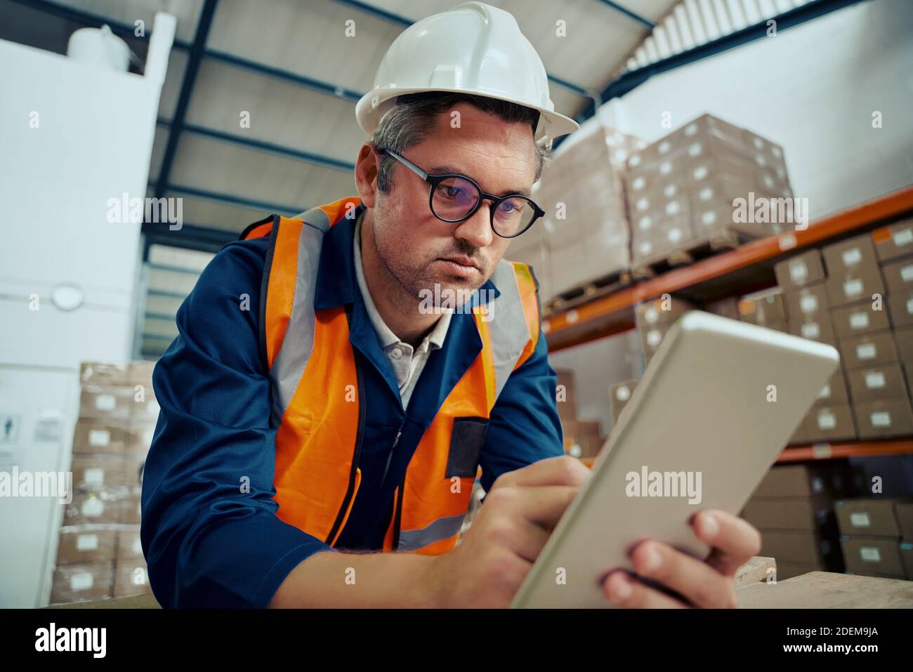 Portrait of a male warehouse worker looking at digital tablet screen in ...