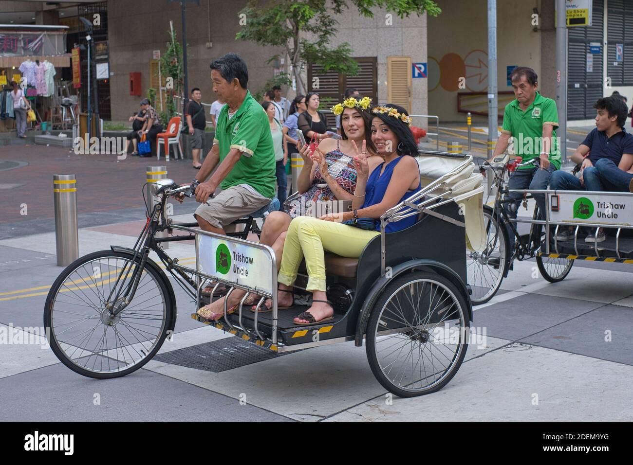Two female tourists flashing the V sign during a trishaw sightseeing ...