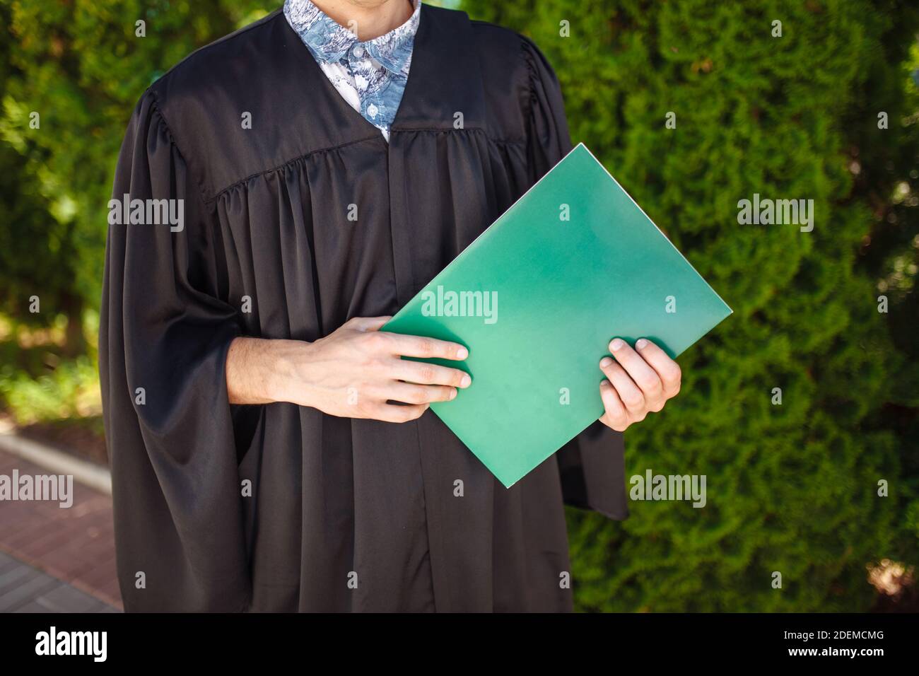 Successful graduate guy, in academic dresses, on graduation posing ...