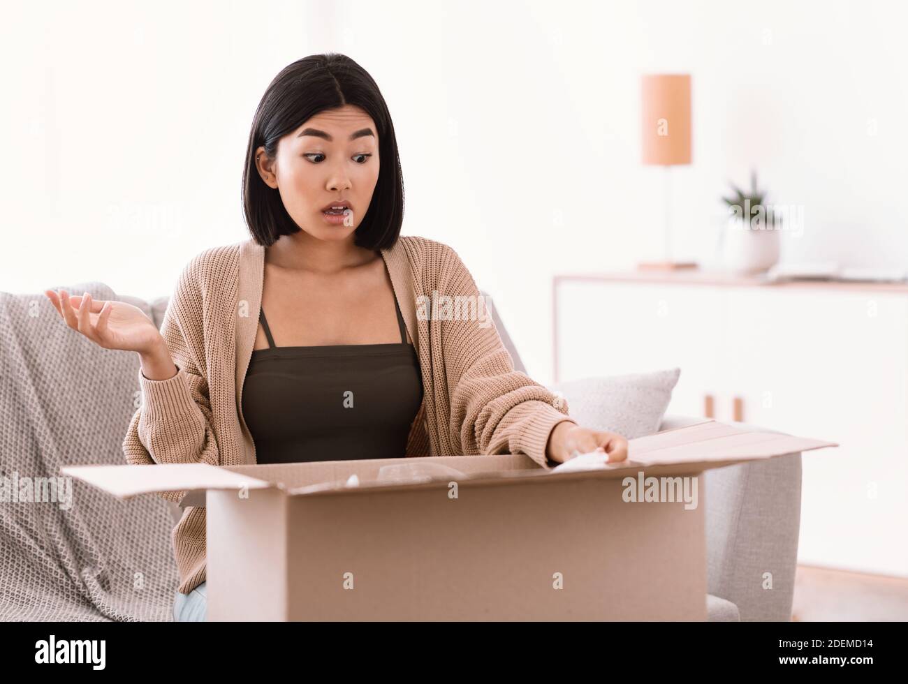Frustrated asian woman unpacking wrong parcel, delivery mistake Stock ...