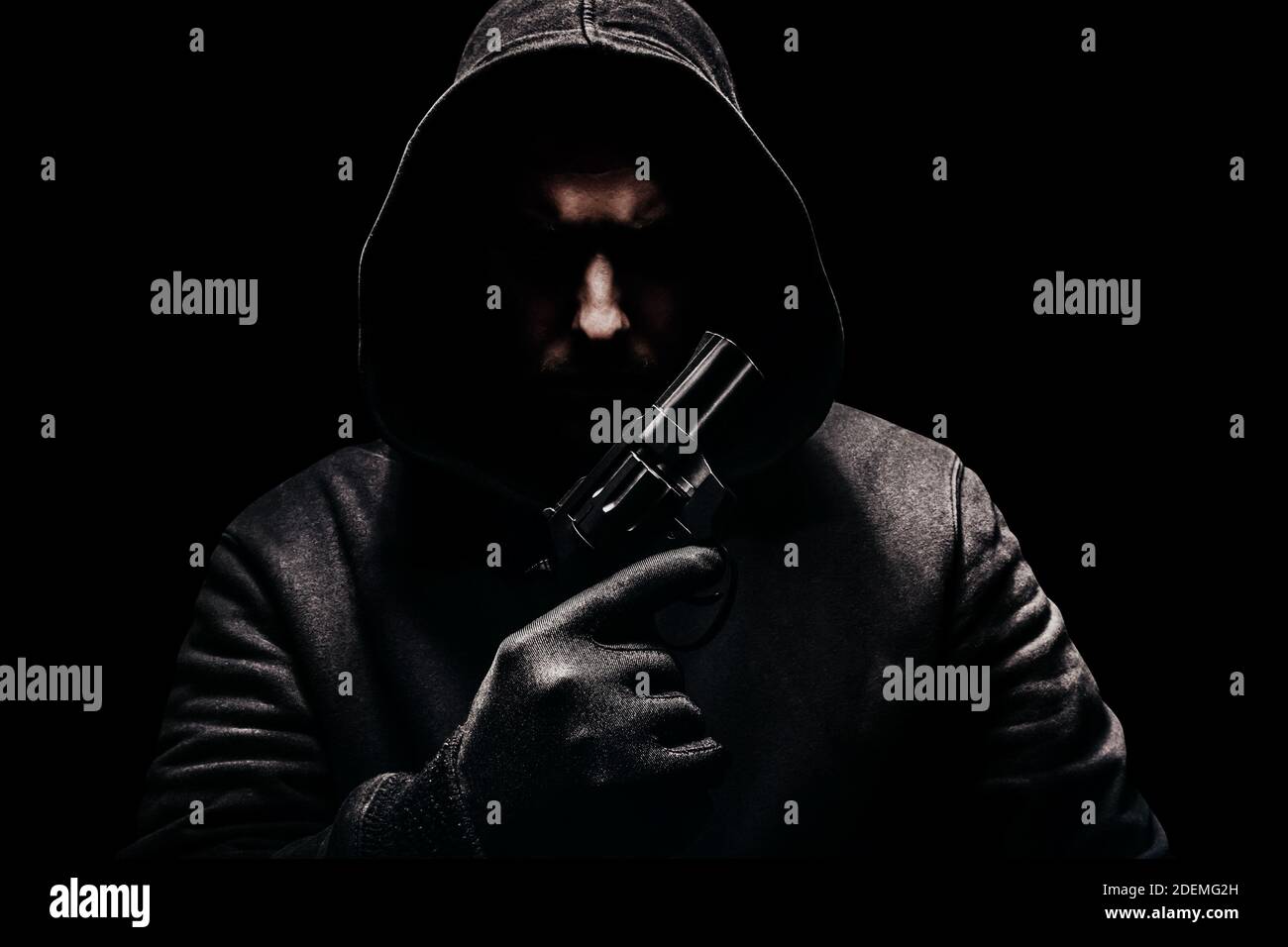 Photo of a creepy horror criminal in black hoodie holding revolver gun ...