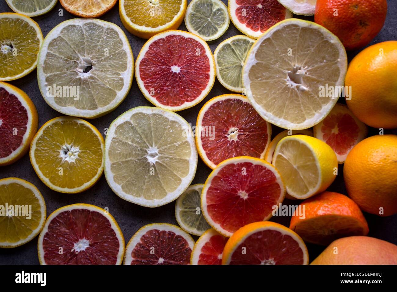 Red orange fruit circles on dark gray background. Citrus texture close ...