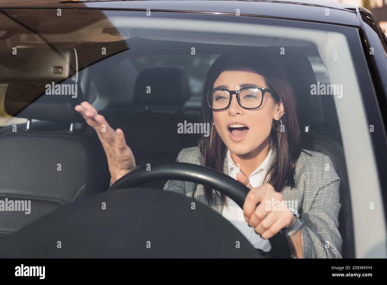 angry woman shouting and gesturing while driving car on blurred ...