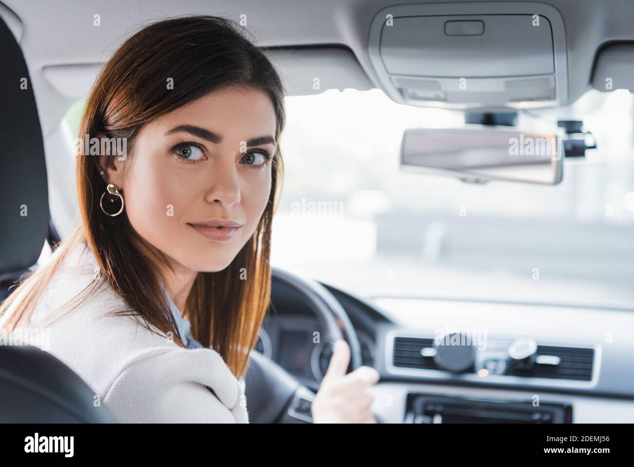 young woman looking back while driving car on blurred background Stock ...