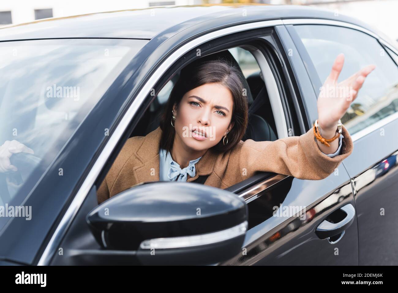 displeased woman looking out from side window and pointing with hand ...