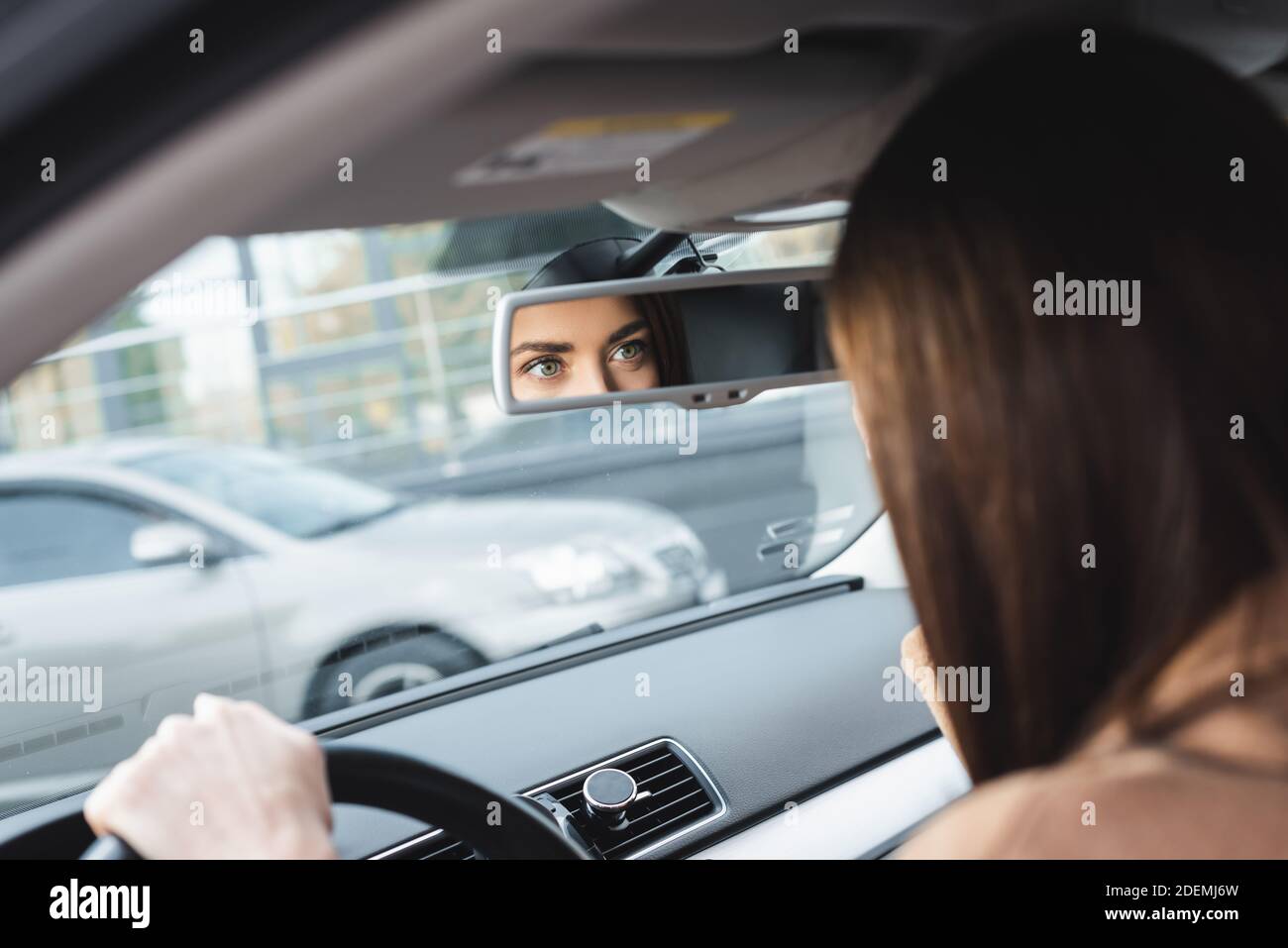 woman driving car and looking in rearview mirror on blurred foreground ...