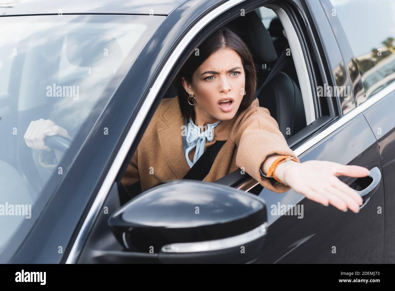 irritated woman shouting and pointing with hand from side window while ...