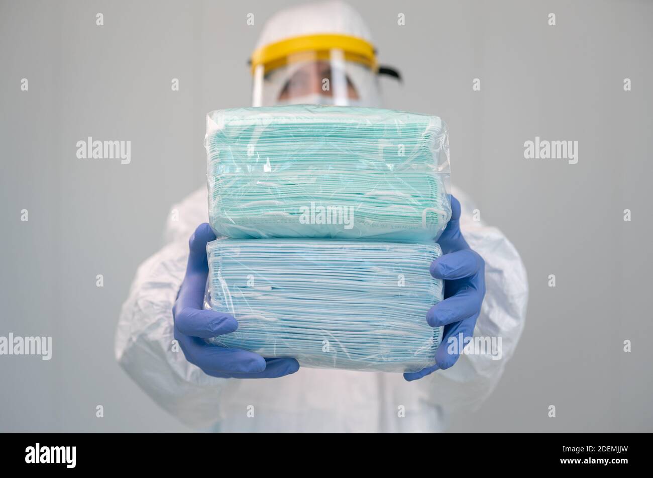 Doctor in PPE with plastic face shield shows the packing of a new ...