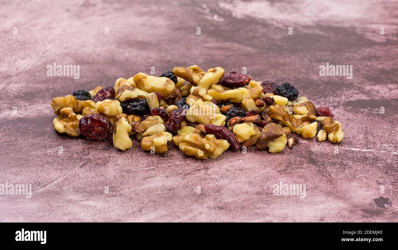 Portion of healthy trail mix with nuts and fruits on a maroon ...