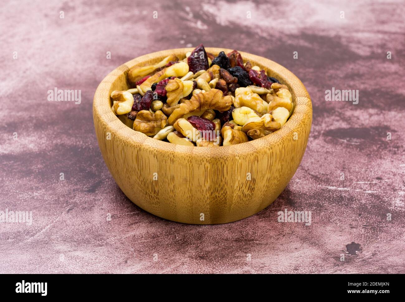 Wood bowl filled with healthy trail mix with nuts and fruits on a ...