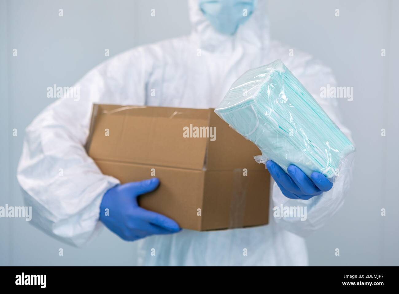 Male nurse wears protective suit with surgical mask unpacking carton ...
