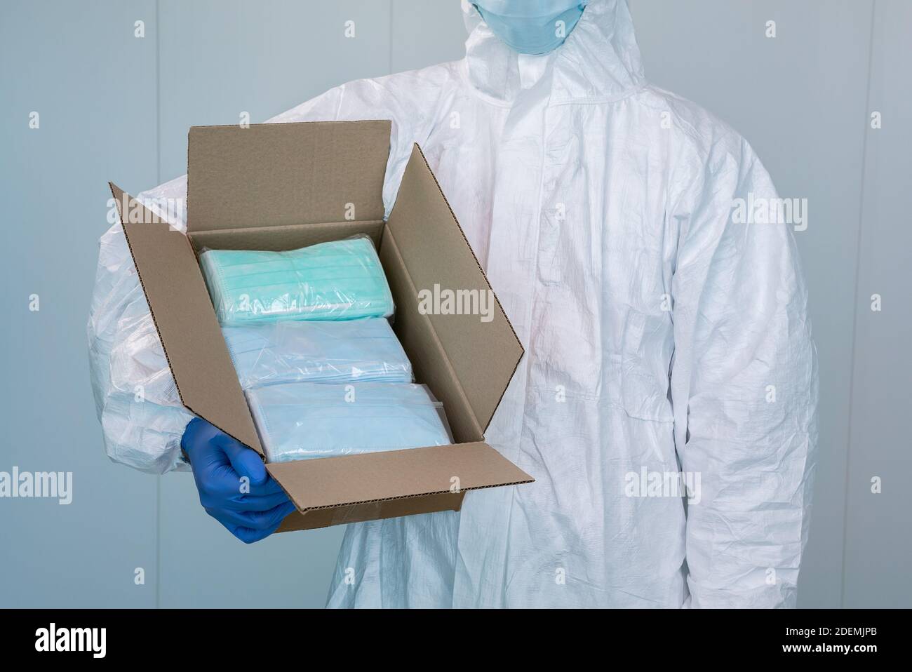 Male nurse wears protective suit with surgical mask unpacking carton ...