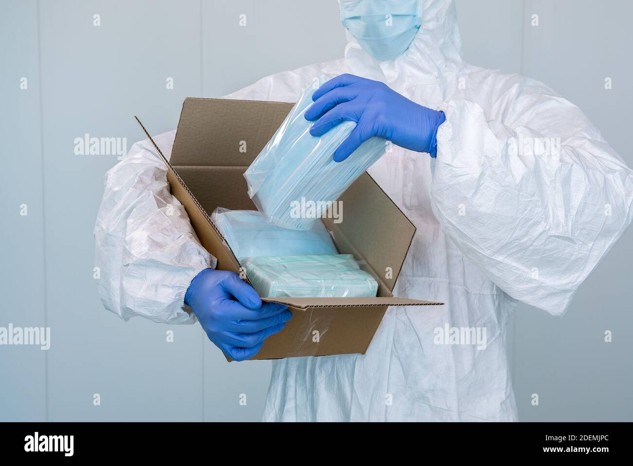 Doctor in PPE and medical mask opens a box and show the packing of a ...