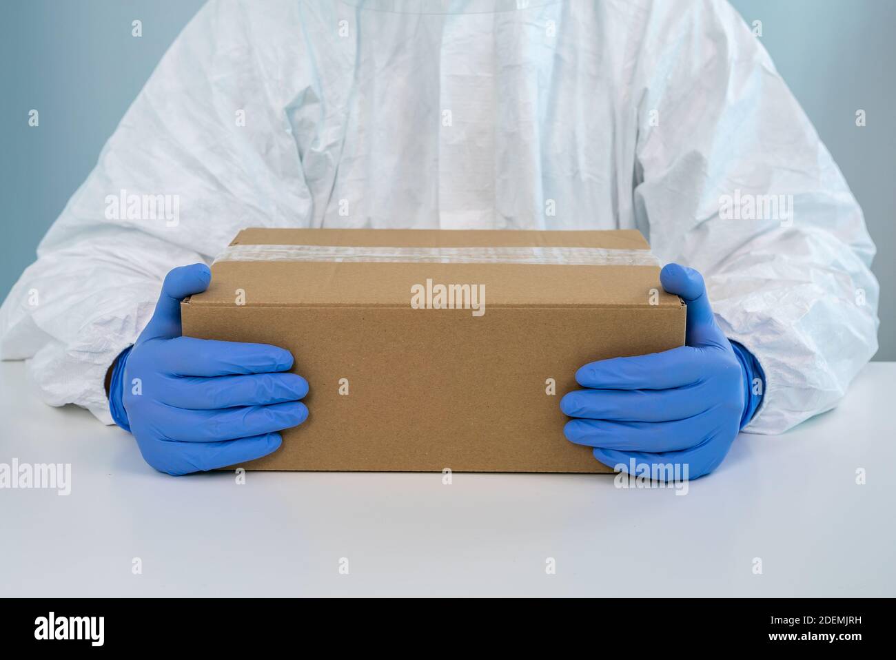 A nurse in a protective suit shows a box with both hands in a hospital ...