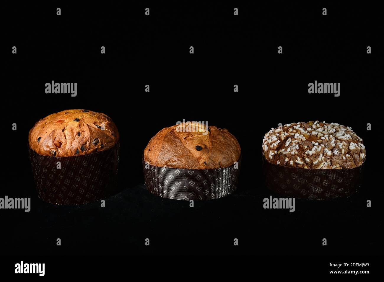 three types of Italian panettone: high, low and with almonds on a black ...