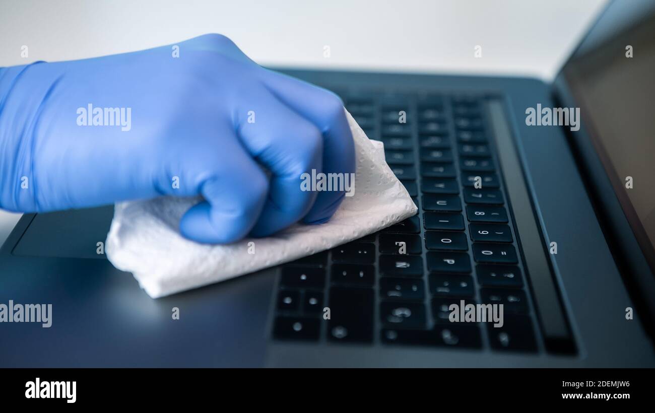 Person cleaning and disinfecting the laptop keyboard to prevent the ...