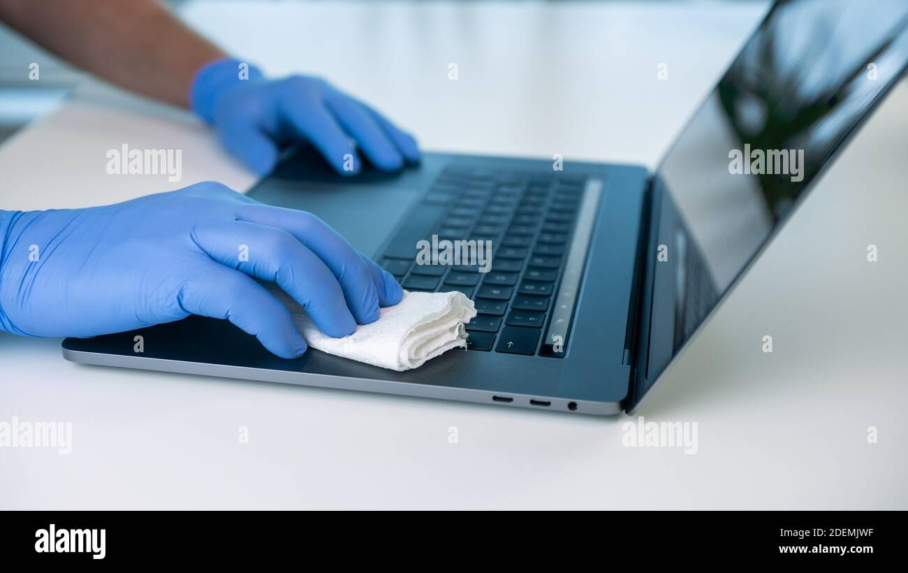 Person cleaning and disinfecting the laptop keyboard to prevent the ...