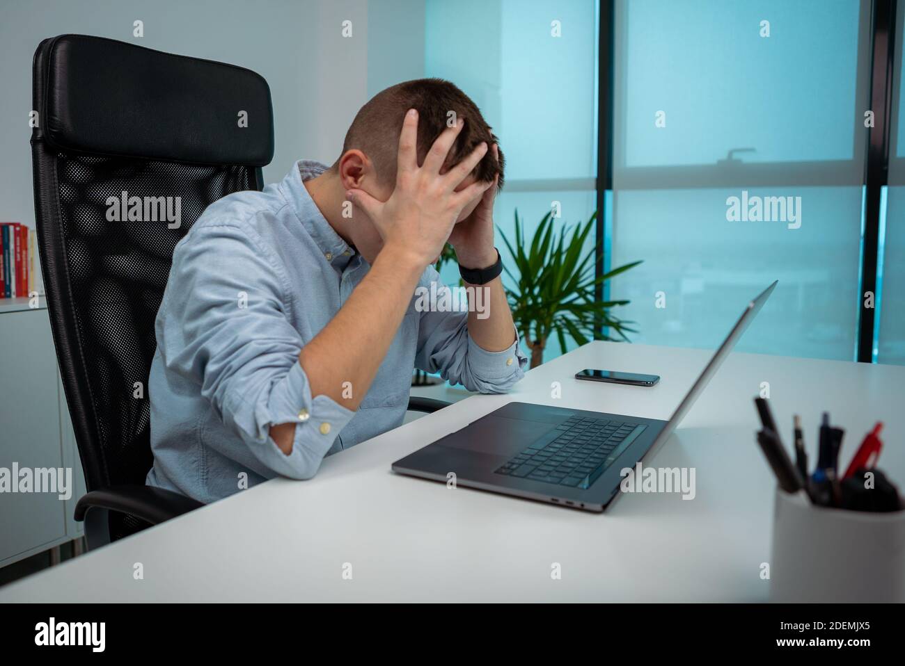 Tired or stressed young businessman sitting in front of computer in ...