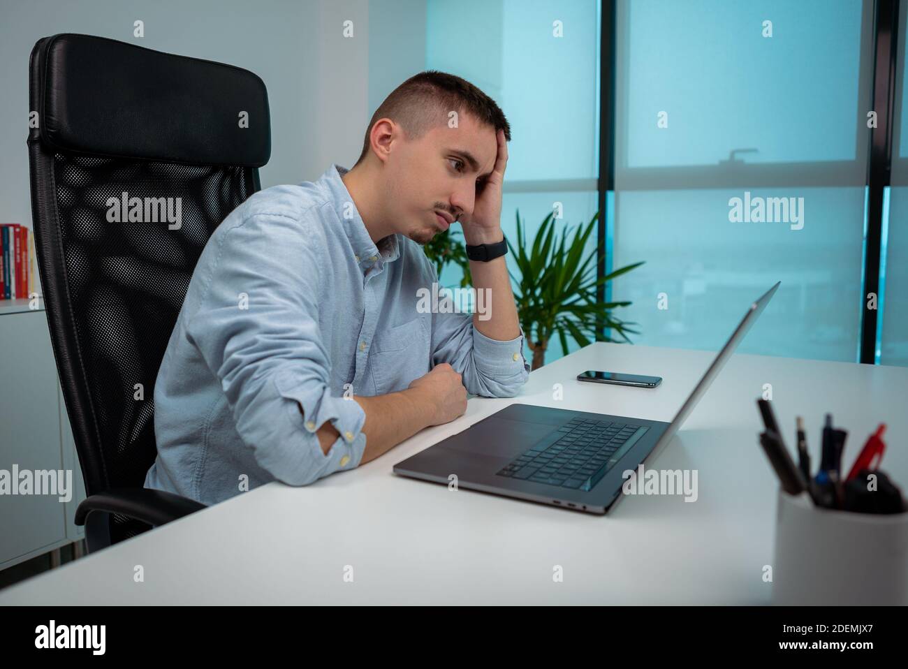 Tired or stressed young businessman sitting in front of computer in ...