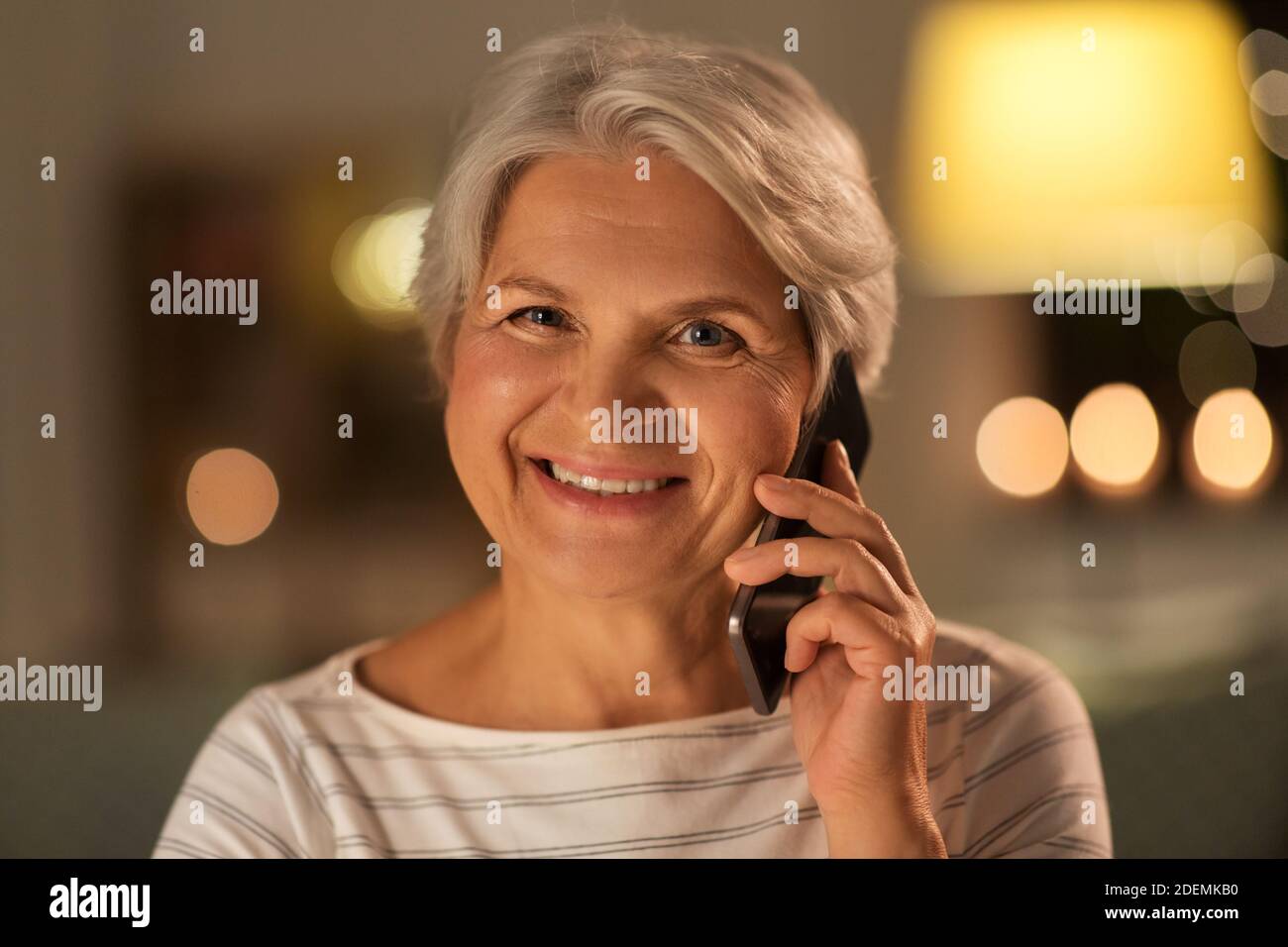 old woman calling on smartphone at home in evening Stock Photo - Alamy