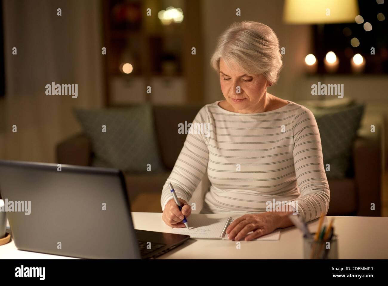 senior woman writing to notebook at home at night Stock Photo - Alamy