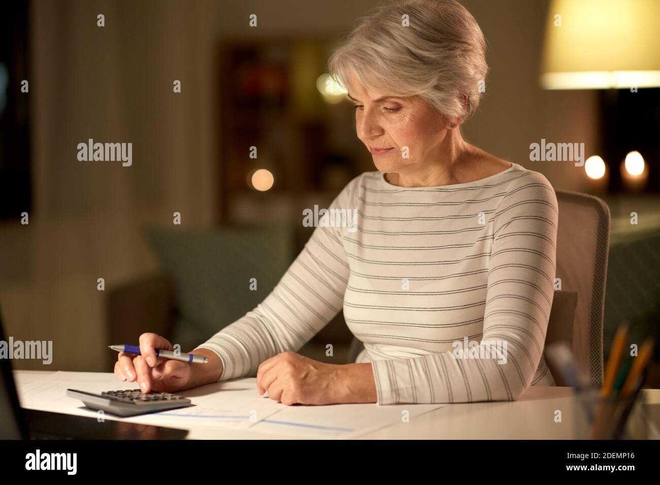 old woman counting on calculator at home at night Stock Photo - Alamy